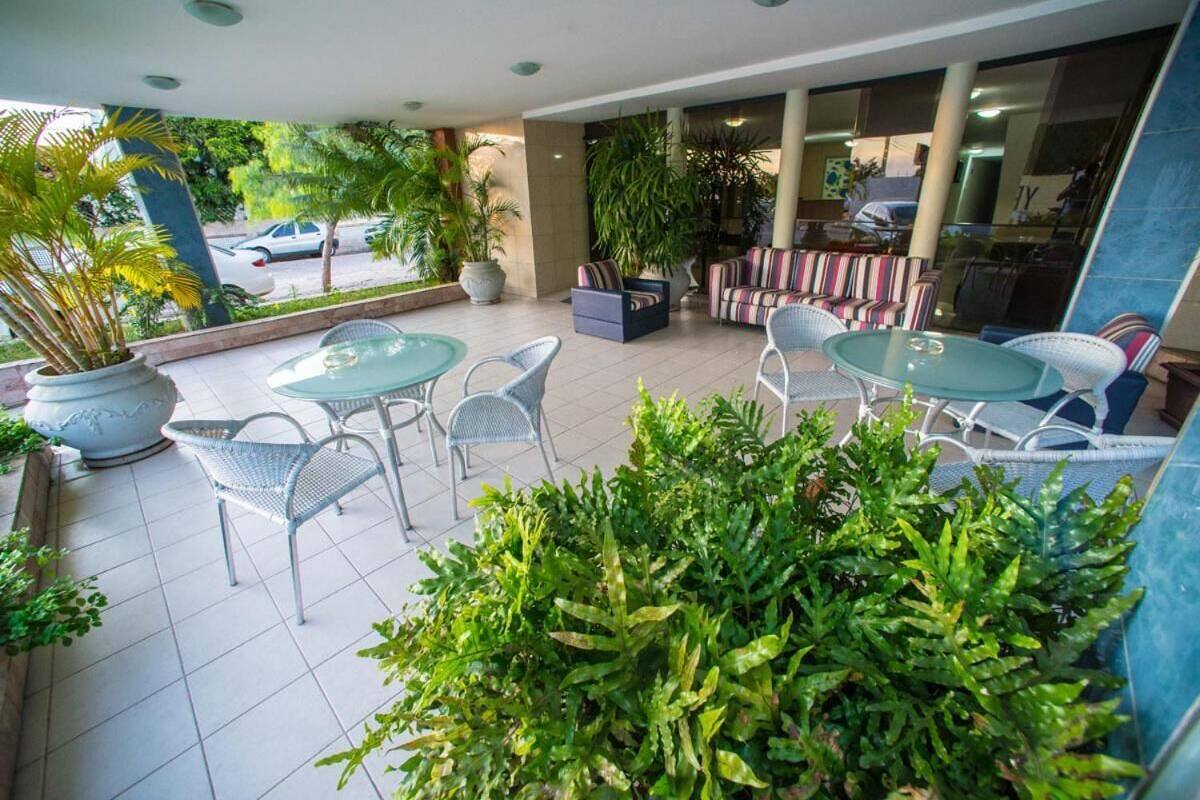 Um hall de hotel com área de estar, plantas em vasos e vista para a rua.