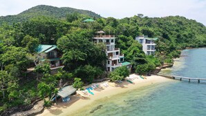 Um resort costeiro com vários edifícios, uma praia de areia e águas turquesa cristalinas.