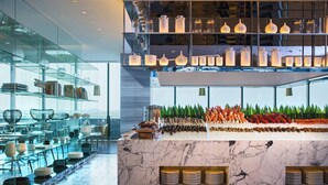 Um restaurante moderno com balcão de mármore, prateleiras de vidro e diversos pratos expostos.