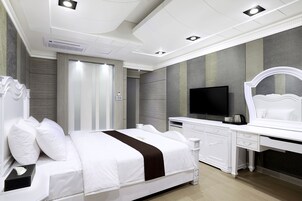 Quarto de hotel moderno com uma cama grande, uma toucador com espelho, uma televisão de ecrã plano e uma secretária.
