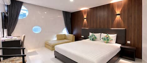 Quarto moderno com uma cama grande, escrivaninha, cadeira e sofá.