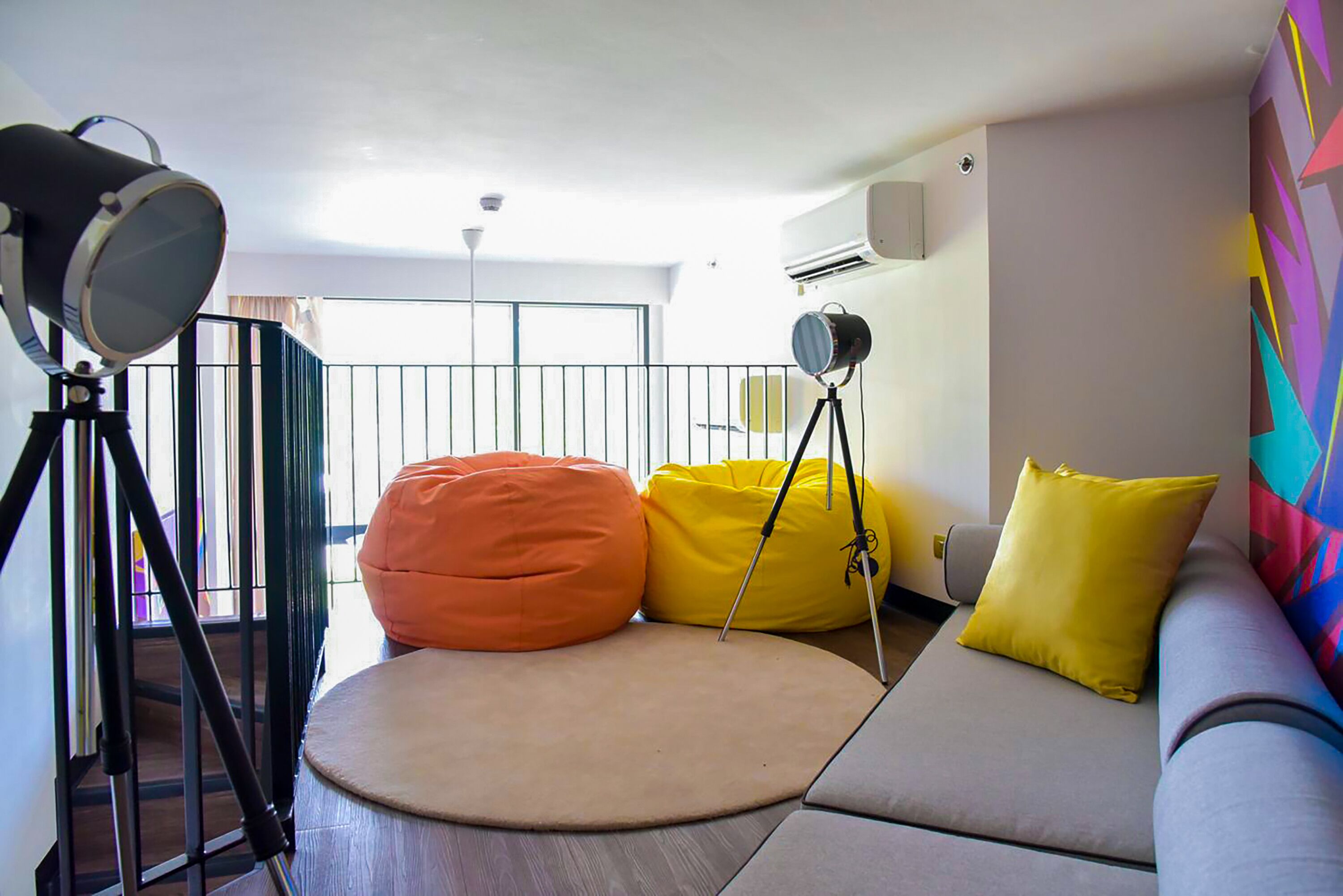 Uma sala de estar moderna com um sofá, dois sacos de feijão, um tripé e uma câmera.