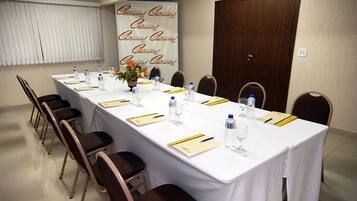 Uma sala de conferências com uma mesa comprida preparada para reuniões, equipada com garrafas de água, cadernos e canetas.