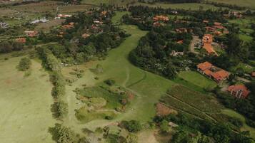 Vista aérea de uma área residencial com casas, campos verdes e um campo de golfe.