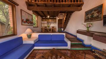 Uma sala de estar com um sofá azul, mesa de centro de madeira e uma escada que leva a um andar superior.