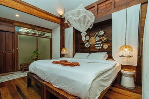 Quarto com cama, abajures, luminária pendente e parede decorada com pratos.