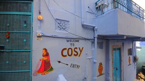 Um edifício com um mural dando as boas-vindas aos visitantes a 'COSY' e uma seta indicando a entrada.