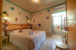 Quarto com cama, mesa de cabeceira, cômoda e janela.