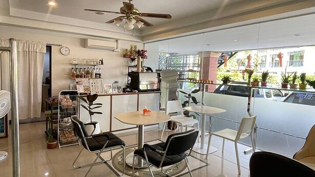 Quarto de hotel moderno com varanda, cozinha compacta e área de estar com cadeiras e mesa.