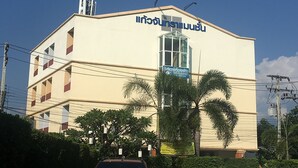 Um edifício com uma placa em idioma estrangeiro, cercado por palmeiras e fios de energia.