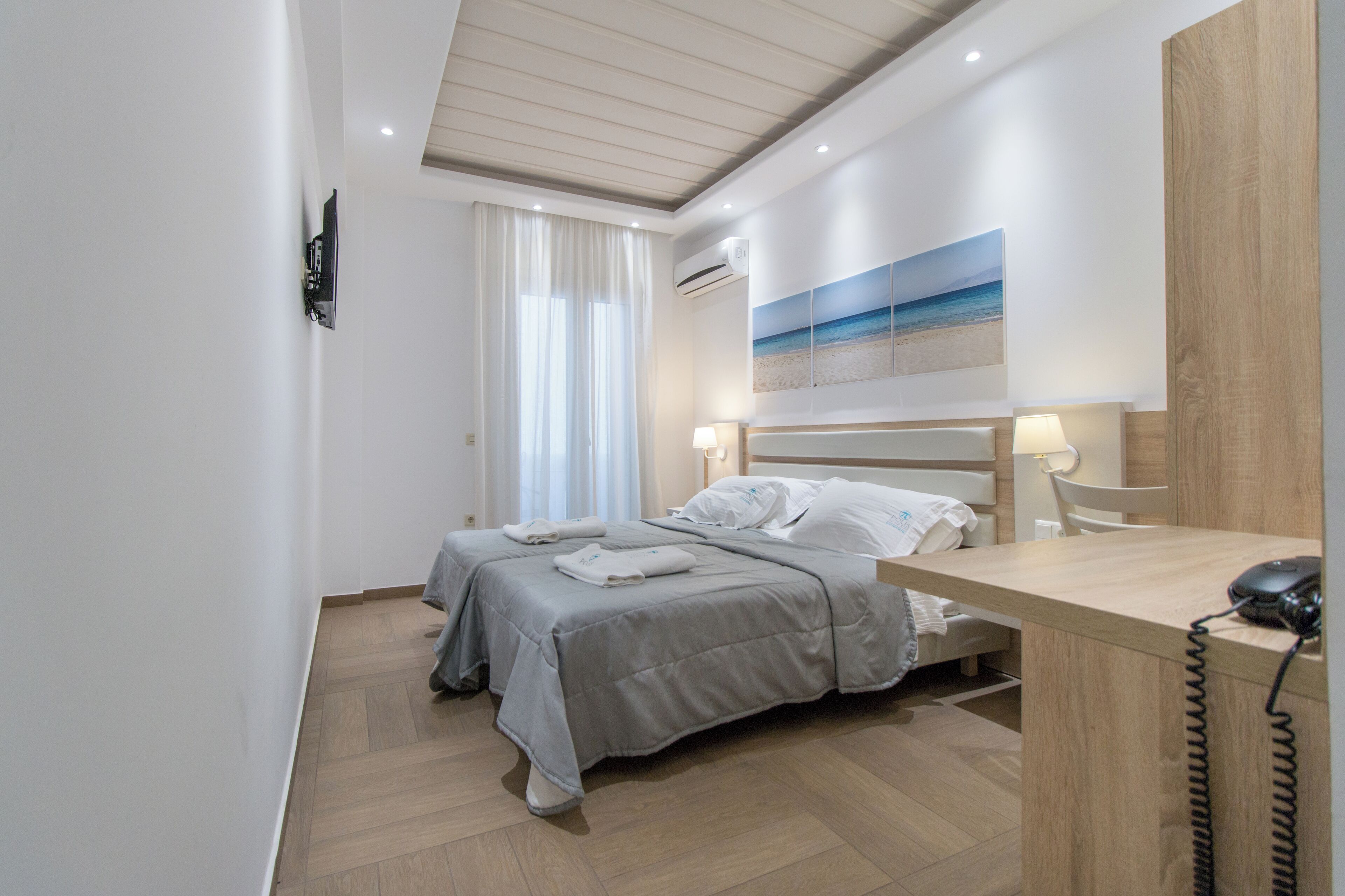 Quarto de hotel com duas camas, uma mesa com telefone e ar condicionado fixado na parede.