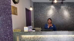 Balcão de recepção com bancada de mármore, um relógio e uma placa com os horários de check-in.