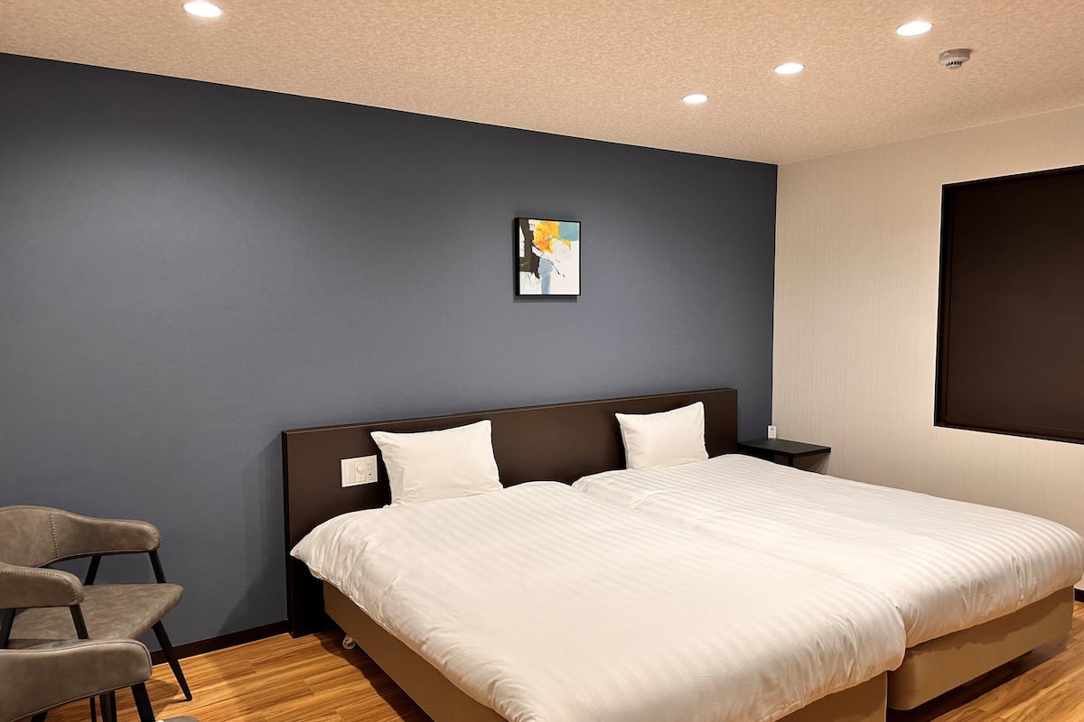 Quarto de hotel moderno com uma cama grande, uma cadeira e um quadro na parede.