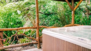 Uma banheira de hidromassagem com estrutura de madeira e vegetação exuberante ao fundo.