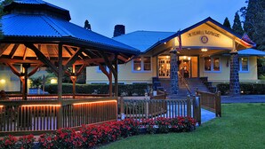 Um edifício com varanda coberta e uma placa com a inscrição 'Kilauea Lodge'.