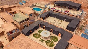 Vista aérea de um resort com vários edifícios, piscina e painéis solares.