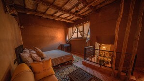Um quarto acolhedor com cama, sofá, tapete estampado e varanda com guarda-corpo.