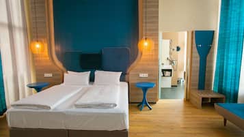 Cama de casal com roupa de cama branca, duas mesas de cabeceira e cabeceira de madeira.