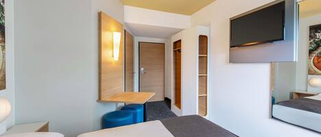 Quarto de hotel moderno com cama, escrivaninha, televisão e guarda-roupa.