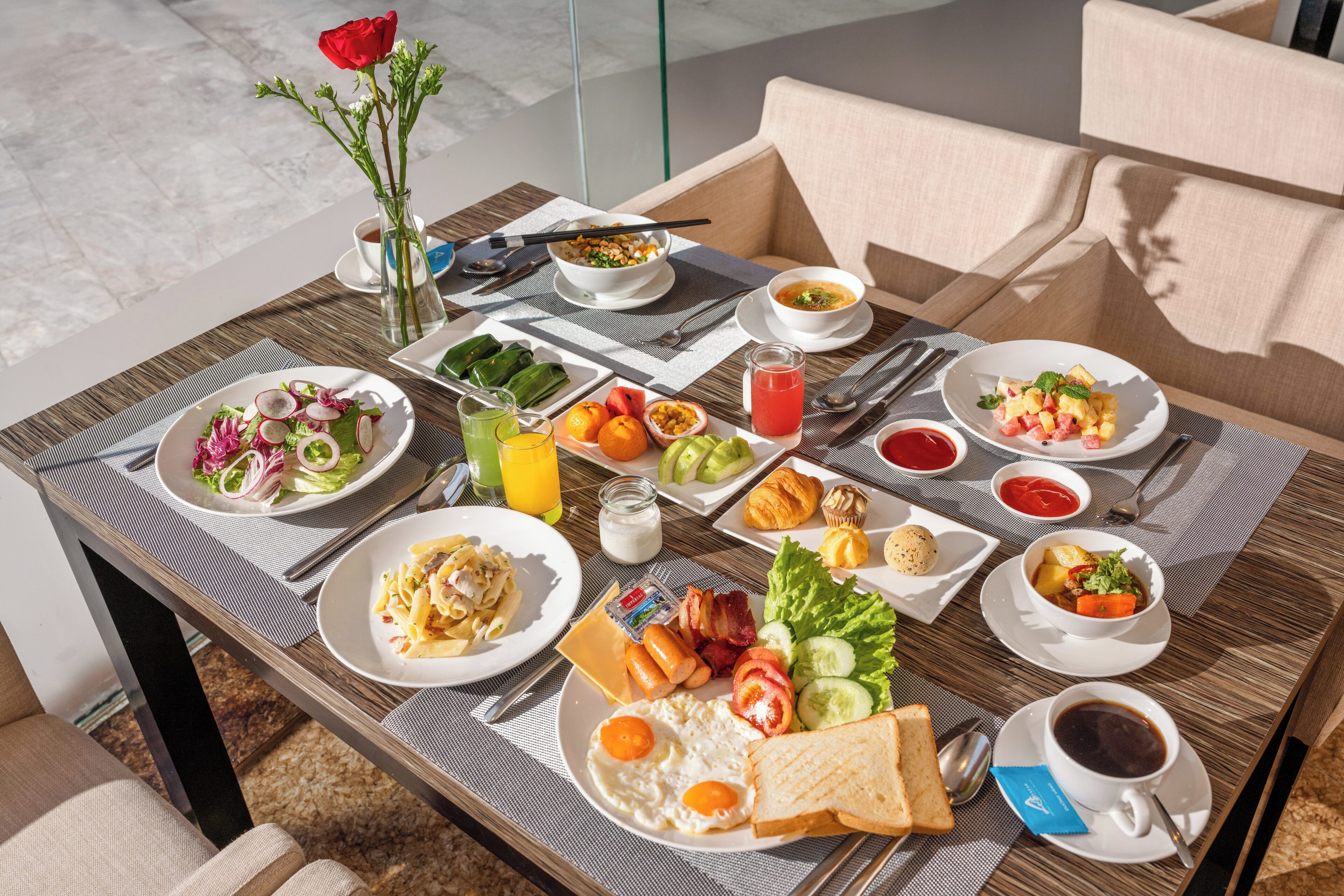 Mesa de café da manhã com diversos pratos, incluindo ovos, torradas e uma salada.