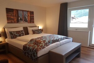 Um quarto com uma cama grande, uma mesa de cabeceira, uma janela com vista para uma paisagem nevada e um quadro sobre a cama.