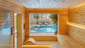 Uma sala de sauna com paredes de madeira e vista para uma piscina ao ar livre.