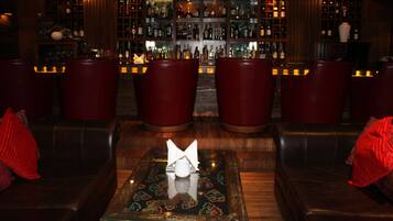 Uma área de bar com assentos de couro, balcão e prateleiras cheias de garrafas.