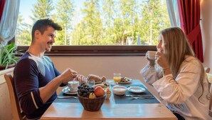 Mesa de café da manhã com cesta de frutas, xícara de café e prato de comida.