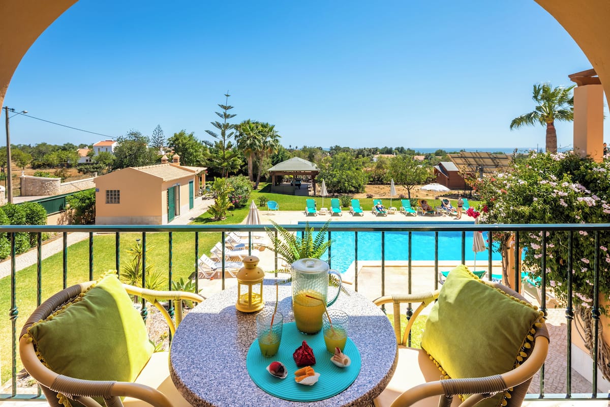 Varanda com vista para uma piscina, mobiliário de exterior e um gazebo.