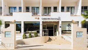 Um hotel de vários andares com uma entrada imponente, um bar lounge e uma escadaria que leva à entrada.