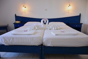 Cama de casal com roupa de cama branca e arranjo de toalha em forma de cisne.