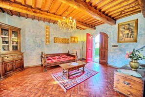 Um quarto com teto de madeira, um lustre, um sofá vermelho, um armário de madeira e uma porta vermelha.