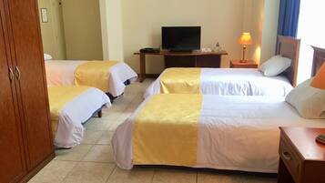 Quarto de hotel com duas camas, televisão, escrivaninha e mesa de cabeceira.