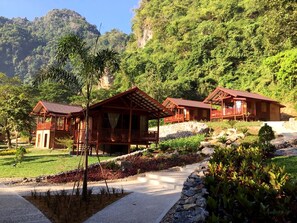Um resort com cabanas de madeira, um caminho pavimentado e vegetação exuberante.