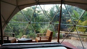 Acomodação em tenda com uma cama, duas cadeiras e uma pequena mesa.