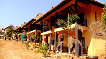 Uma fileira de edifícios em estilo tradicional com telhados de palha, varandas e um calçada pavimentada.