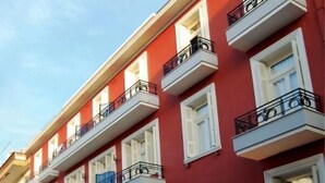 Um edifício vermelho com várias sacadas, molduras de janela brancas e grades pretas.