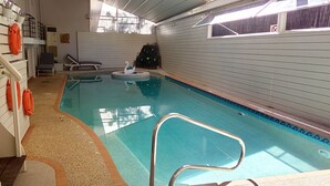 Piscina interna com piso revestido, prancha de mergulho e uma pequena fonte.