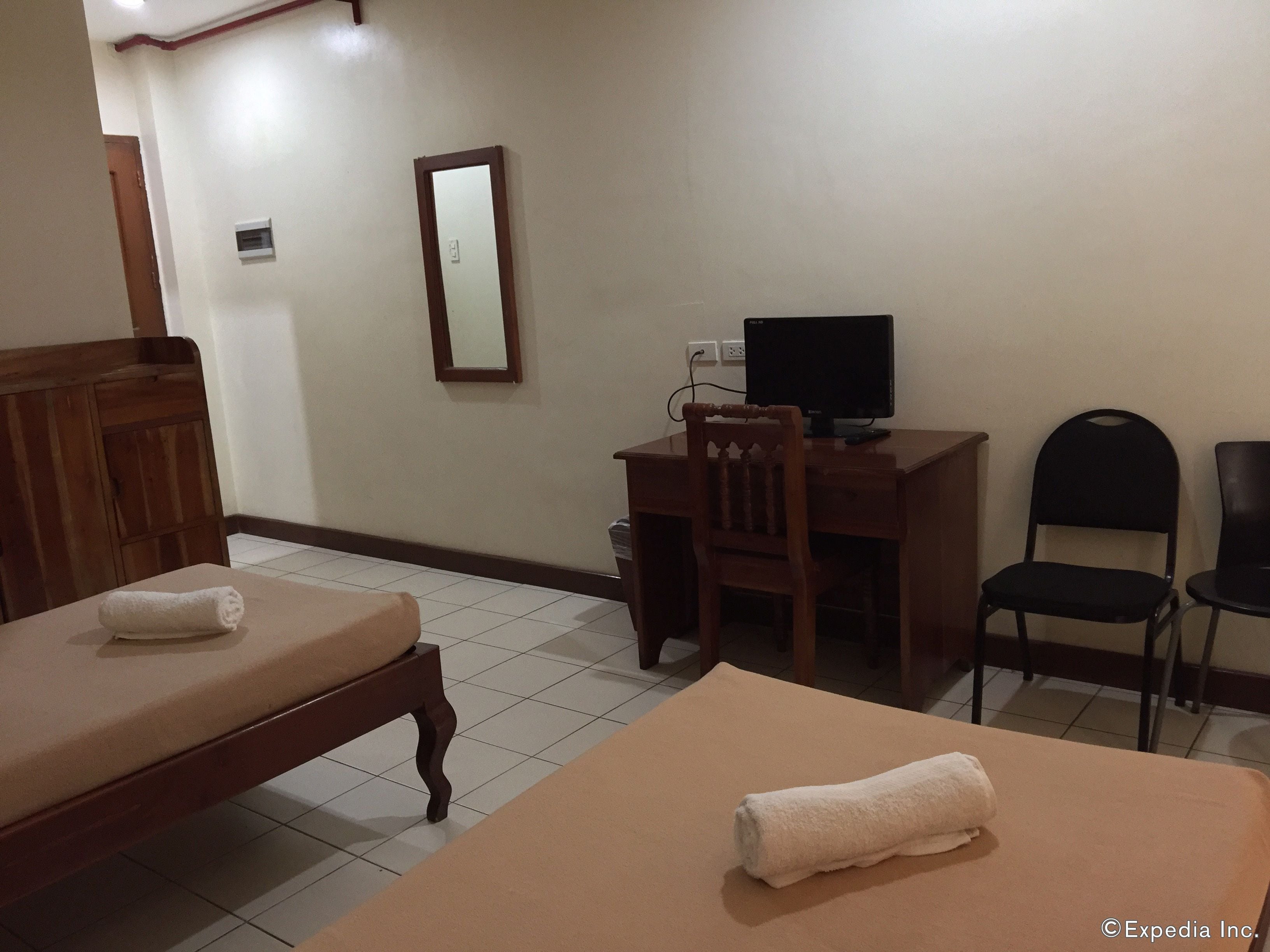 Quarto com duas camas, uma escrivaninha com computador e uma cadeira.