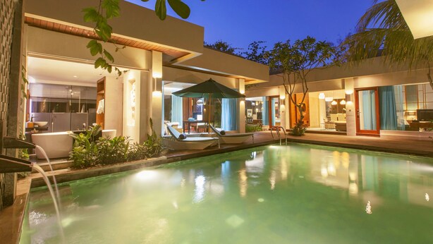 Um hotel moderno com piscina, área de estar externa e interior bem iluminado.