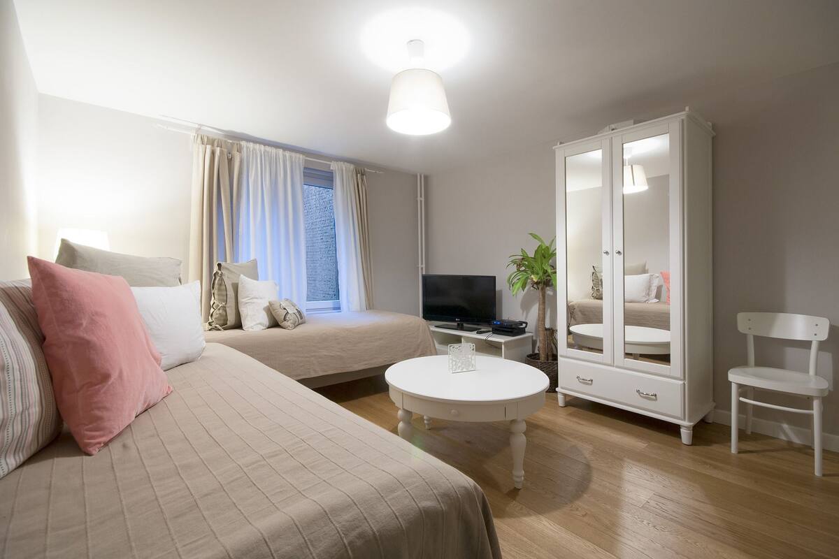 Quarto com cama, televisão, guarda-roupa e uma pequena mesa.