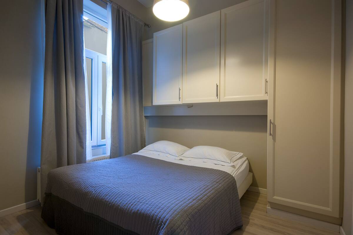 Quarto com cama, cortinas e guarda-roupa.