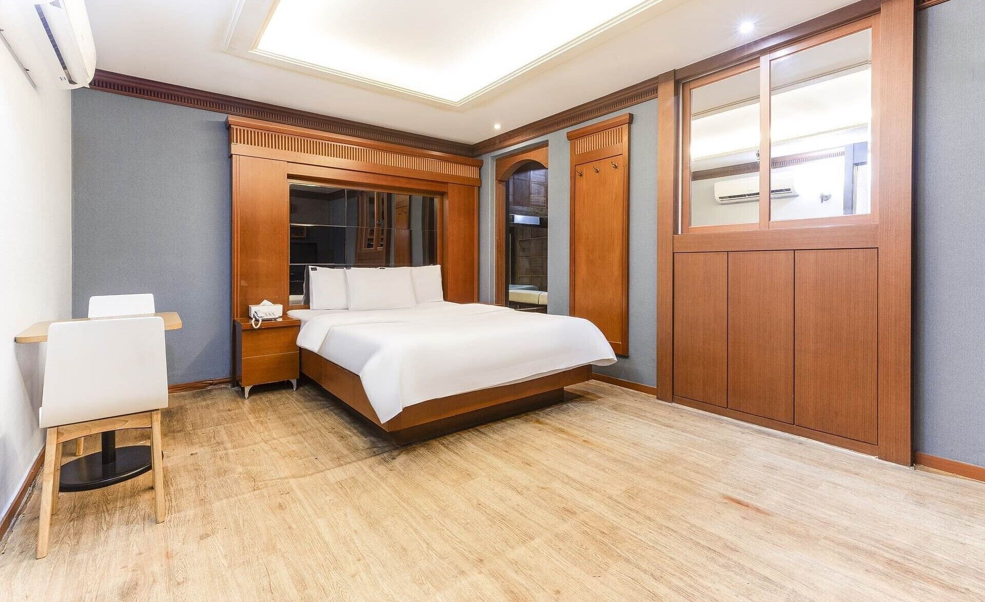 Quarto de hotel com cama, mesa de cabeceira, cadeira e guarda-roupa.