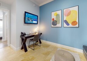 Um espaço de escritório moderno com uma mesa, cadeira e uma TV montada exibindo um site.