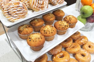 Uma bandeja com muffins e donuts sobre uma mesa.