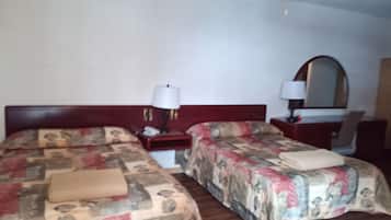 Quarto de hotel com duas camas, uma escrivaninha, uma cadeira, um abajur e um espelho.