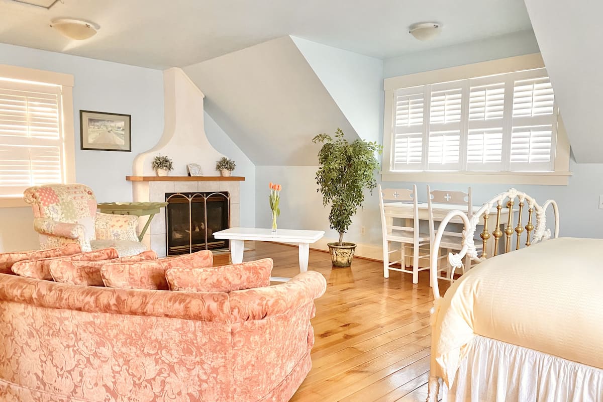 Um quarto aconchegante com lareira, um sofá, uma mesa de jantar com cadeiras e uma cama grande.