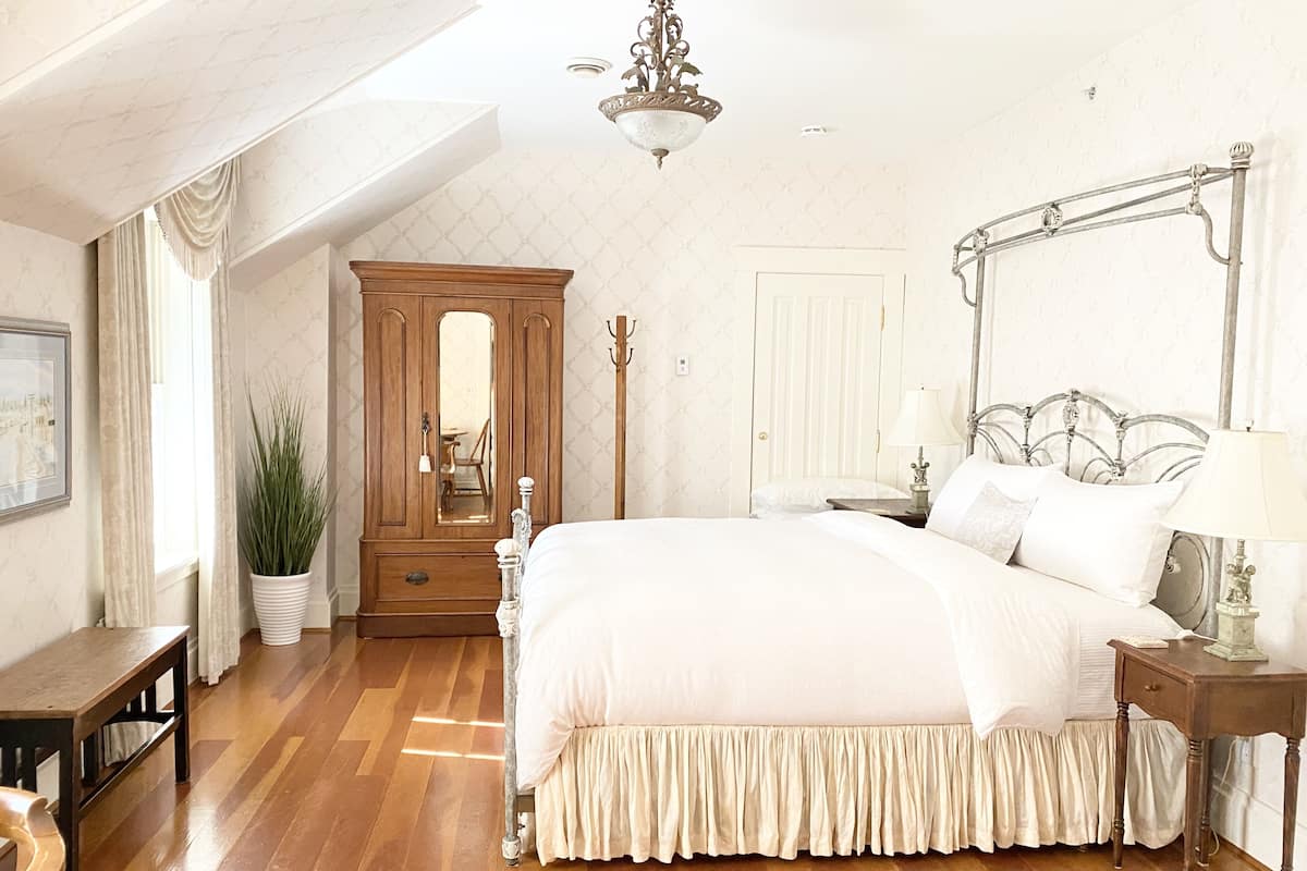 Quarto com uma cama grande, guarda-roupa de madeira e um lustre.