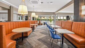 Um restaurante moderno com assentos de couro, mesas redondas e luminárias pendentes.