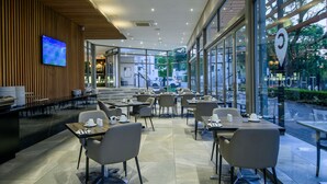 Restaurante moderno com televisão na parede, janelas amplas e vista para o exterior.
